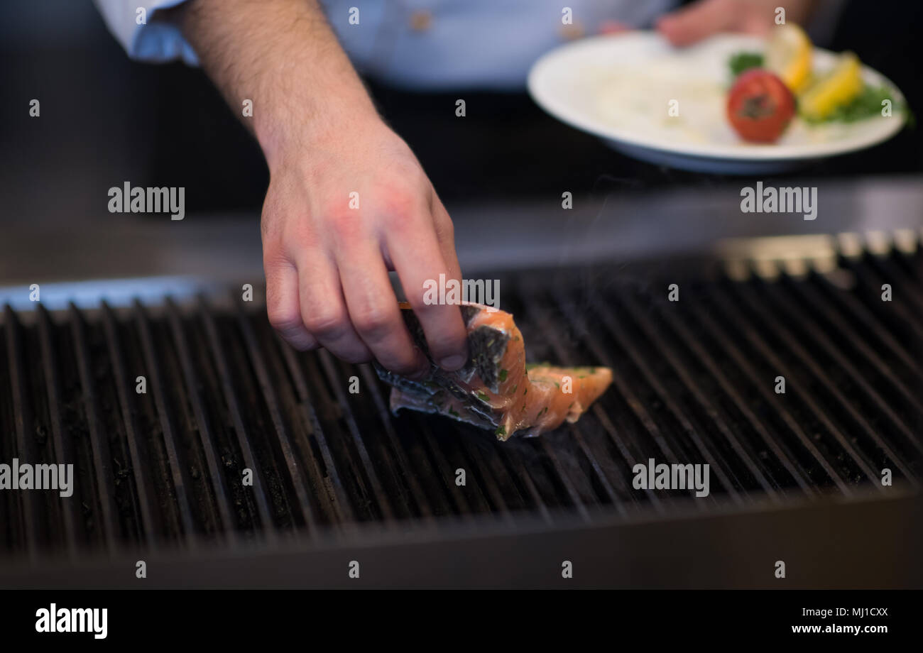 Master chef hands cooking grilled salmon fish with potatoes on a ...