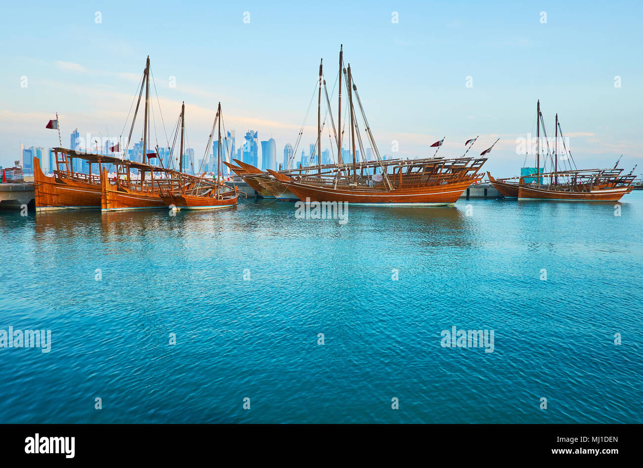 Traditional dhow boats are moored in harbor, the modern skyscrapers of ...