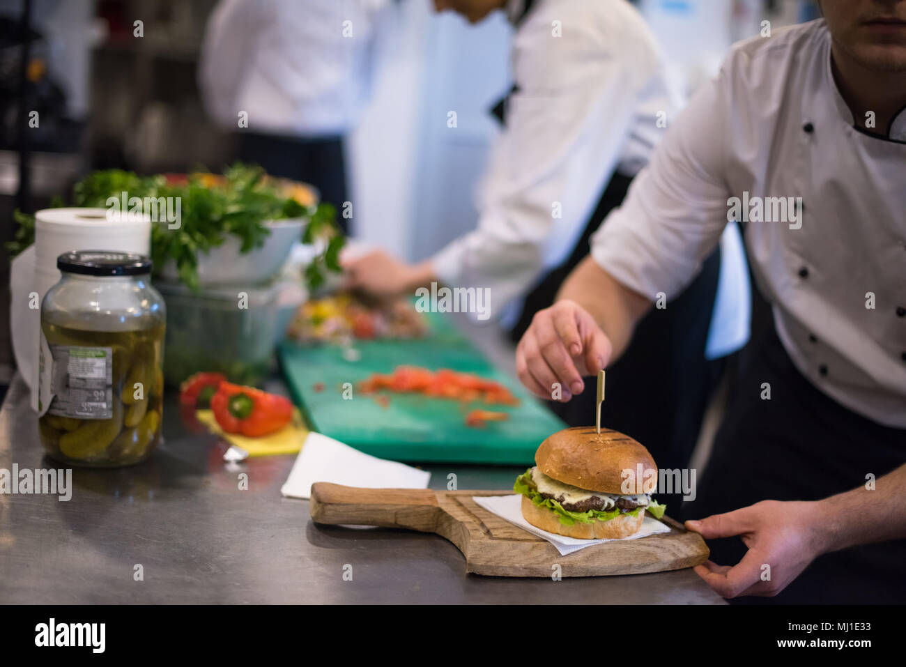 master chef putting toothpick on a burger in restaurant kitchen Stock ...