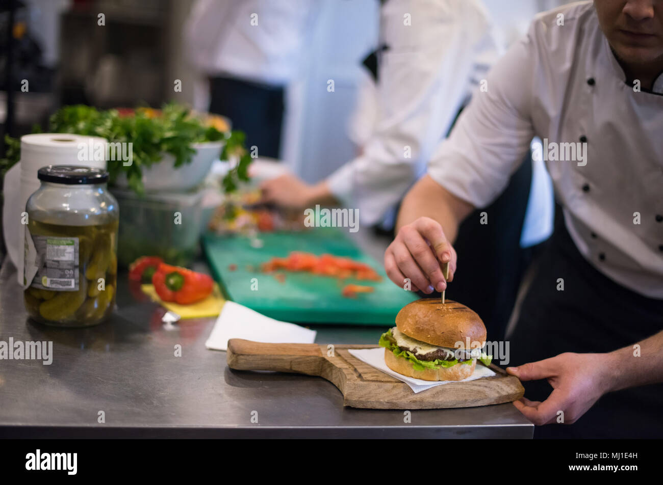 master chef putting toothpick on a burger in restaurant kitchen Stock ...