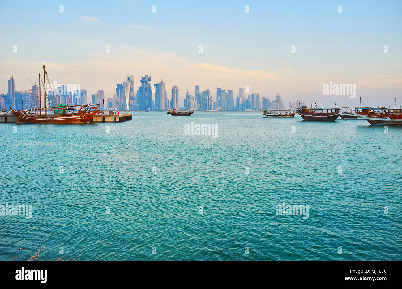 The harbor of Doha with docked wooden dhow boats and ripples on water ...
