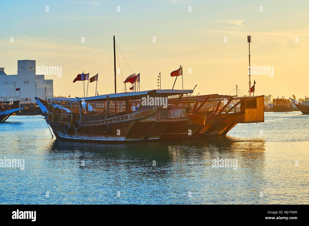 The sunrise sky behind the dhow boats in Doha harbor, neighboring with ...