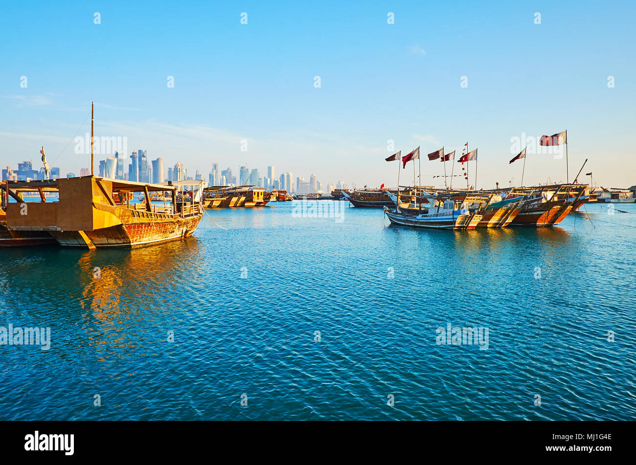 The wooden dhow boats in Doha harbor and numerous skyscrapers, covered ...