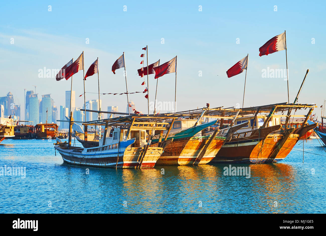 Traditional dhow boats with flags of Qatar are docked in harbor of Doha ...
