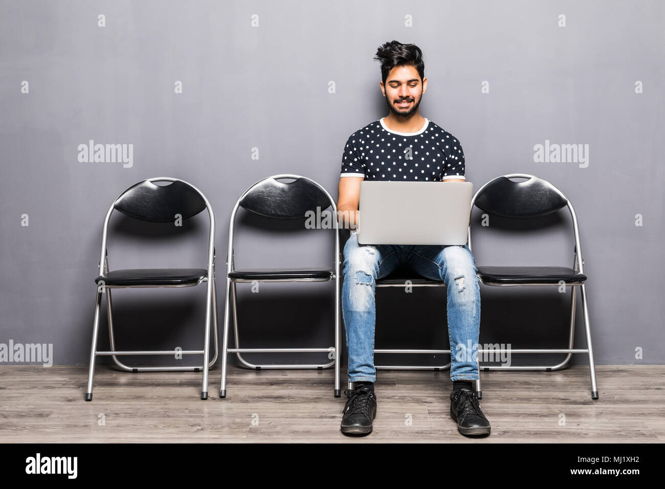 Young man in suit sitting on chair with laptop and waiting for job ...
