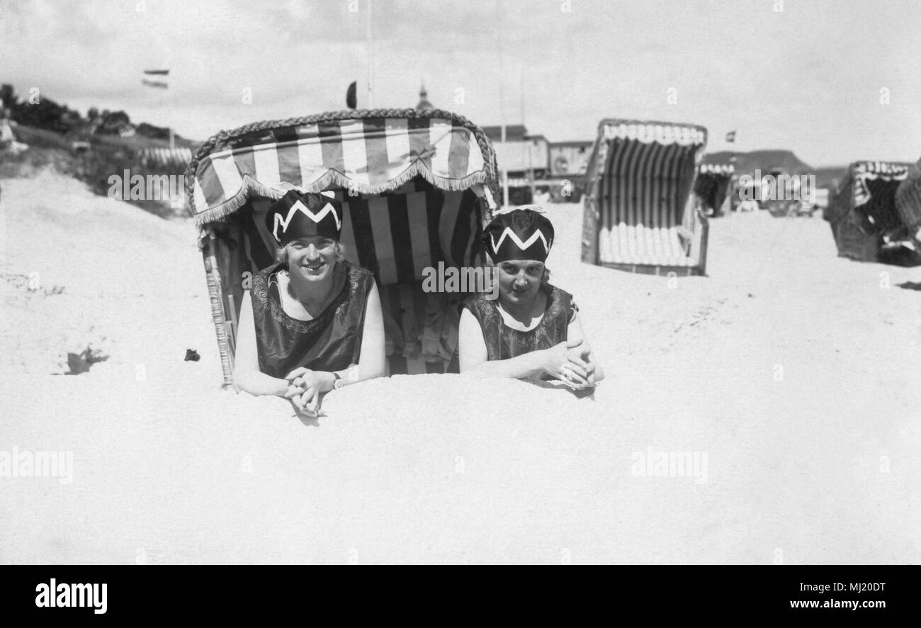 Holiday, two women lying on the beach in front of a beach chair, 1920s ...