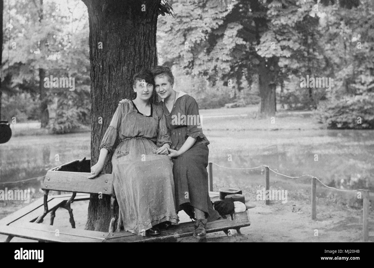 Excursion into the countryside, two friends sitting under a tree posing ...