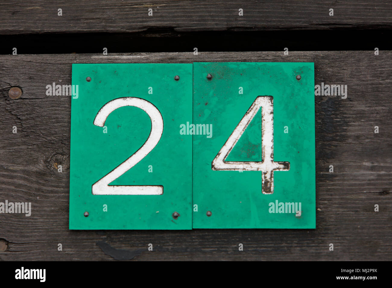 Sign with number 24 in white on green background mounted on wooden ...