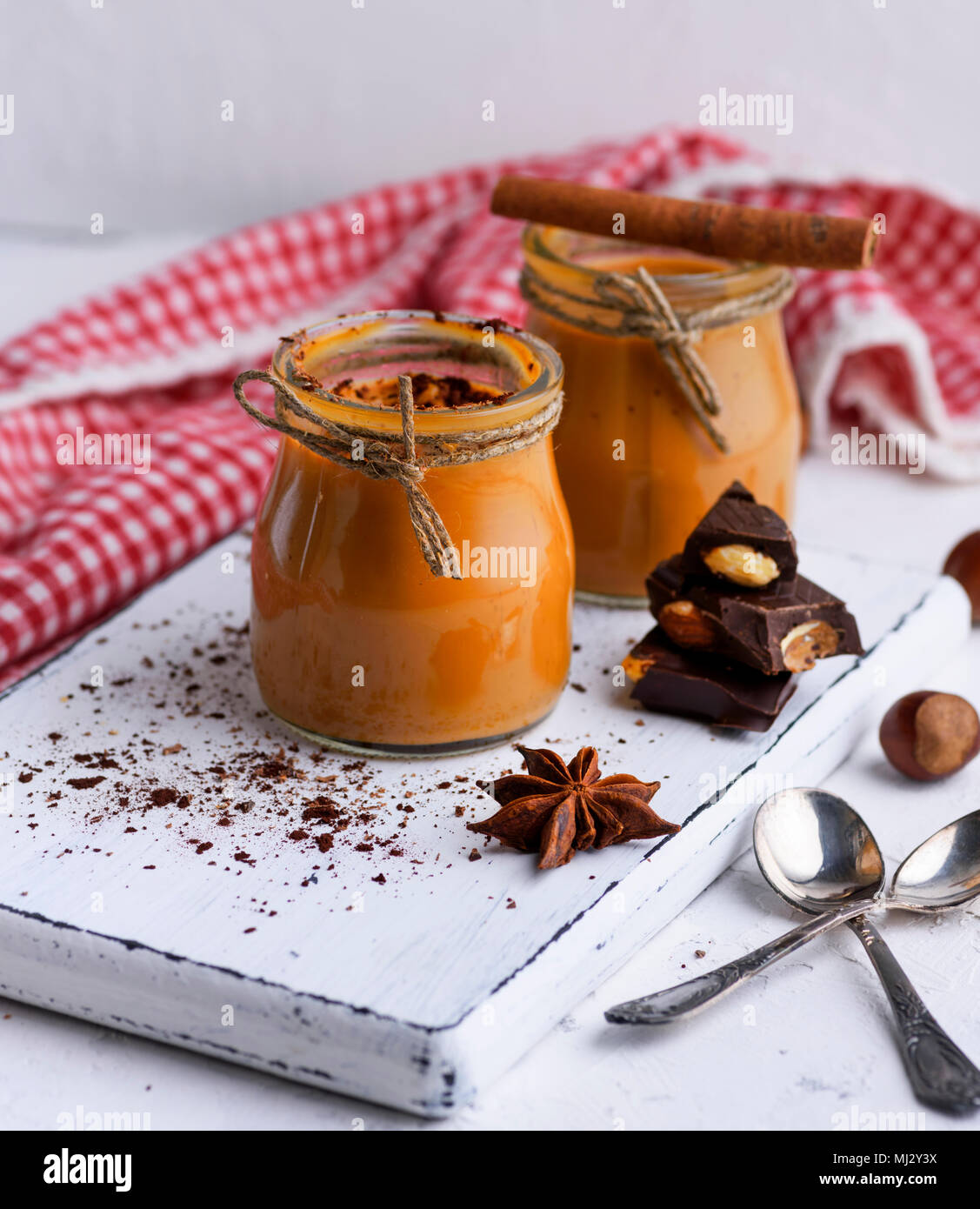 Caramel dessert Toffee in a glass jar on a white rectangular wooden ...