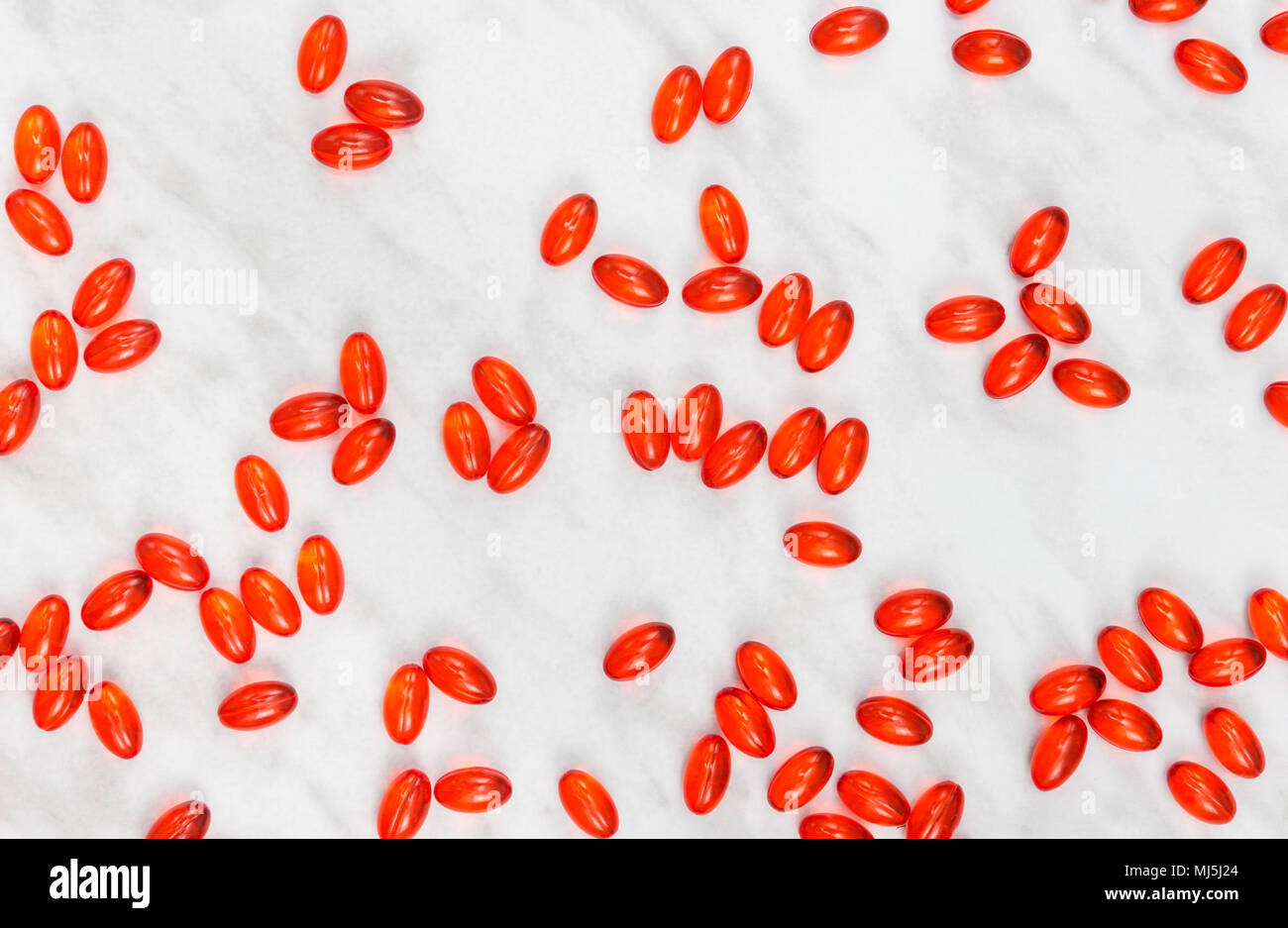Red shiny pills on marble background. Capsules with medicine Stock ...
