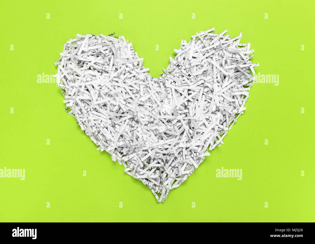 Heart made of shredded paper, on bright green background. Recycling ...