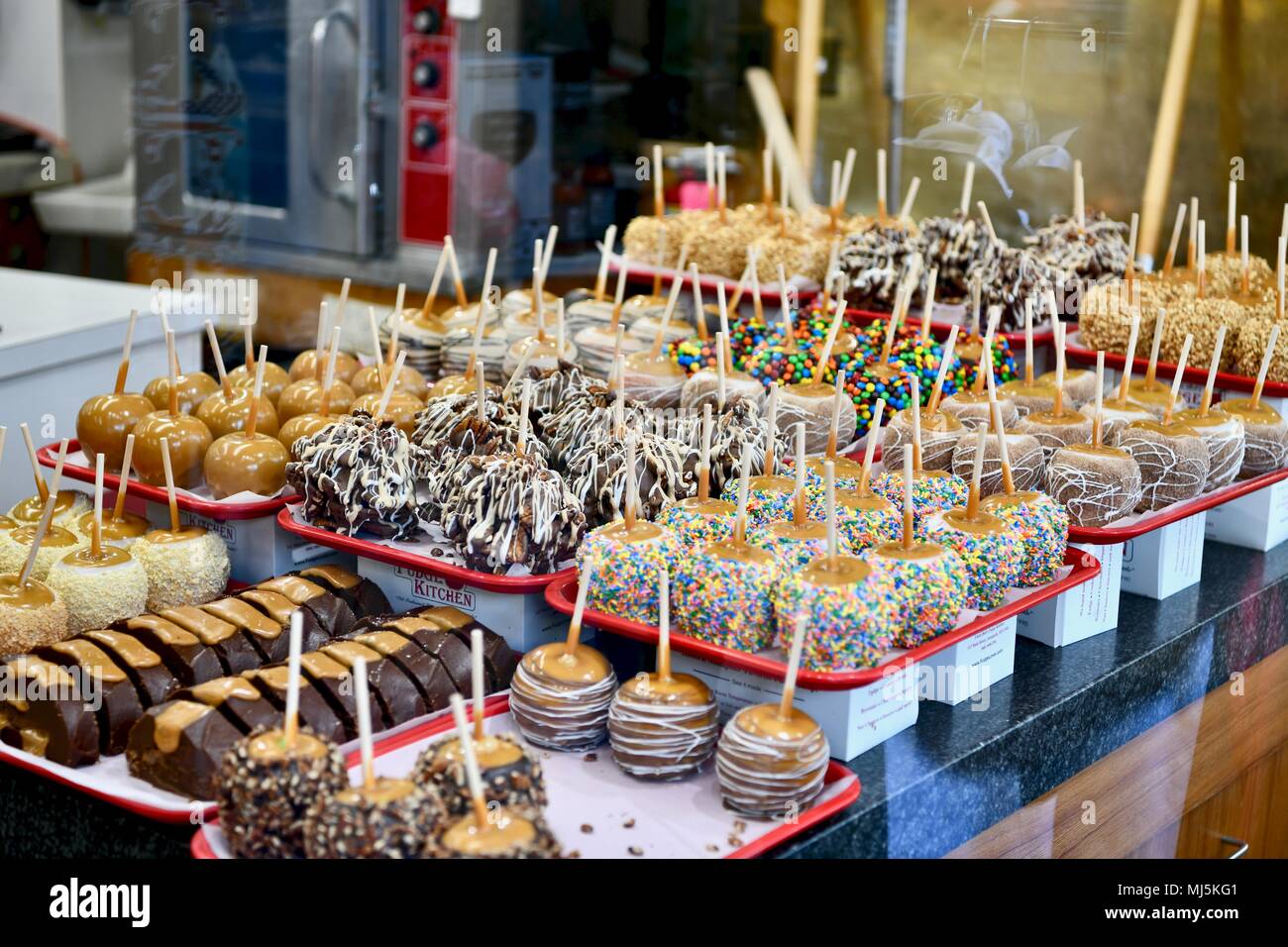 Assortment of candied apples displayed through a the storefront window ...