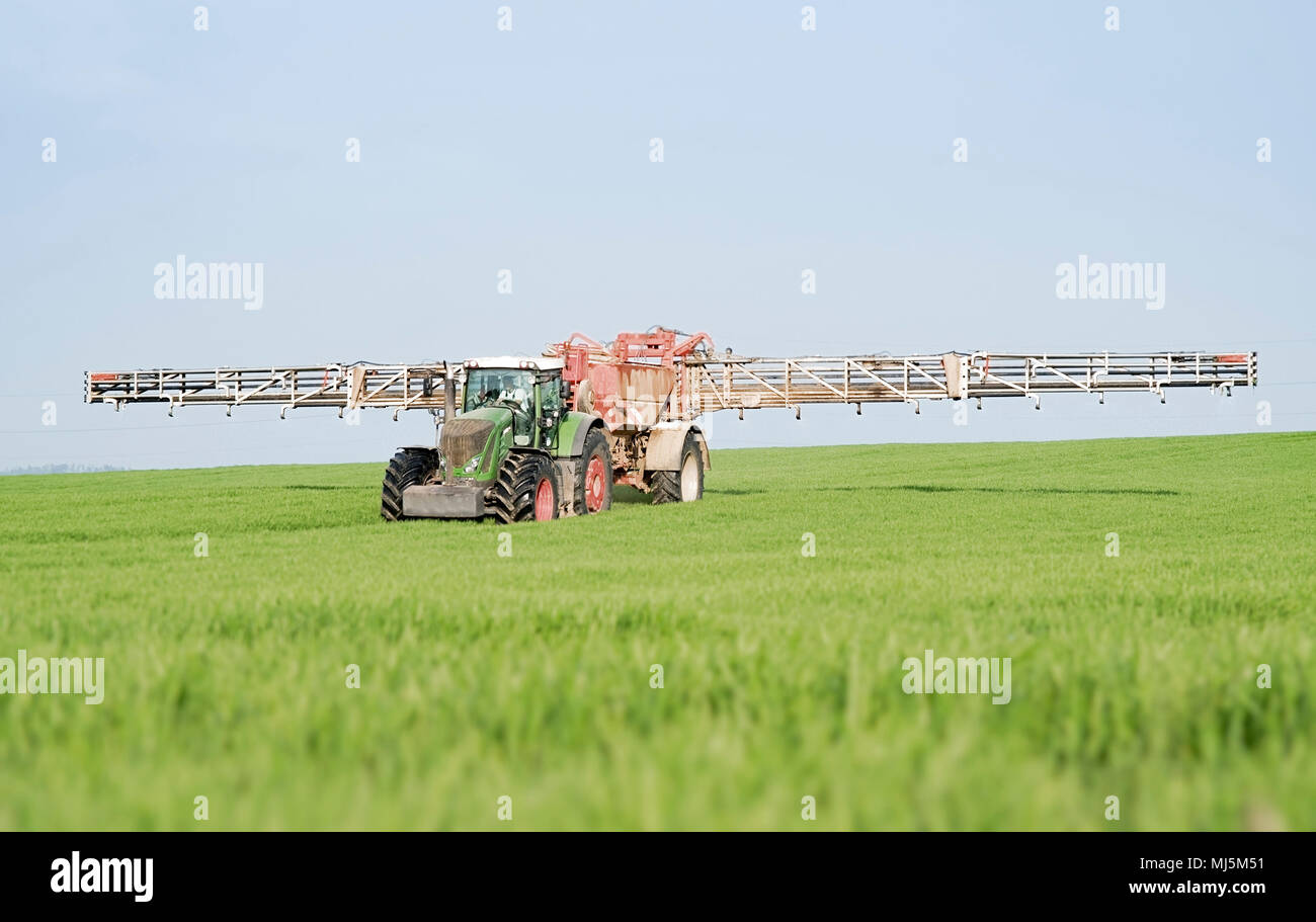 Tractor spraying wheat field with sprayer Stock Photo - Alamy