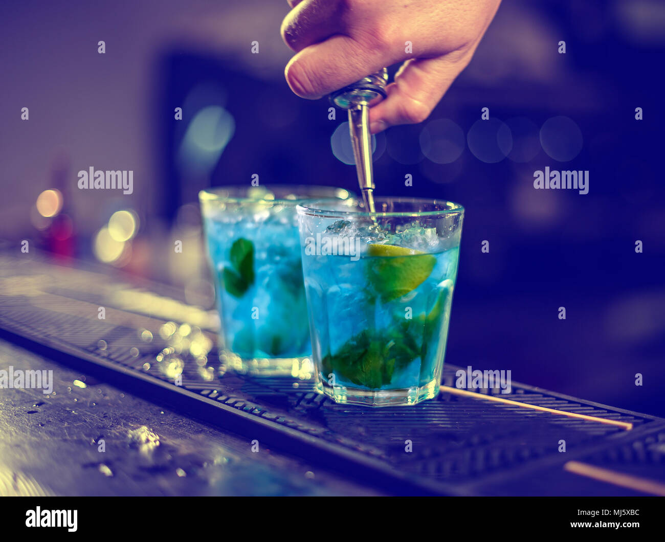 Bartender is pouring blue syrup into the glass with ice cubes on the bar counter Stock Photo - Alamy