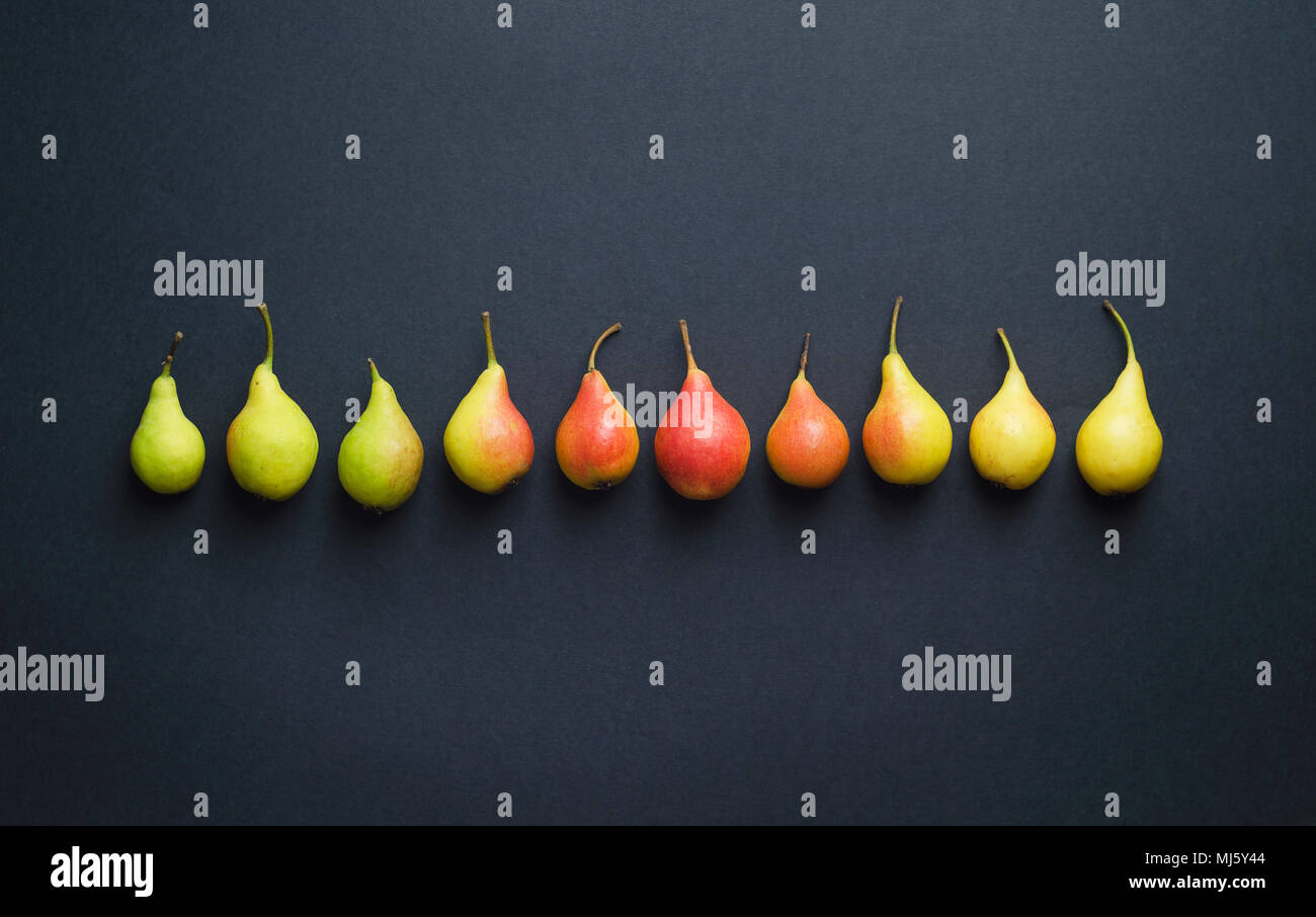 Multiple colorful pears organized in a row over black background Stock ...