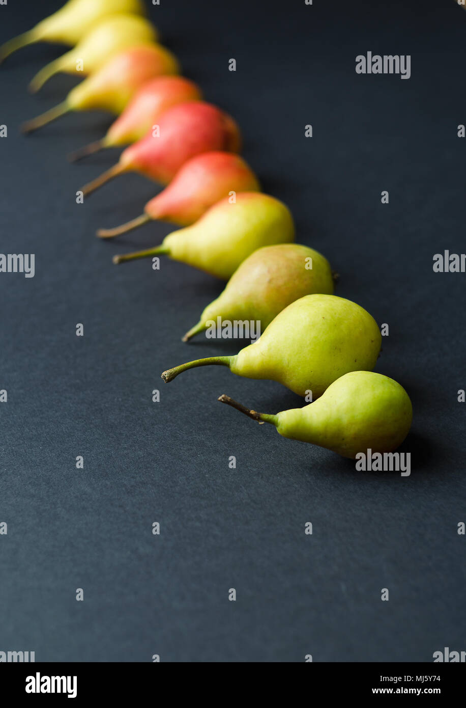 Multiple colorful pears organized in a row over black background Stock ...