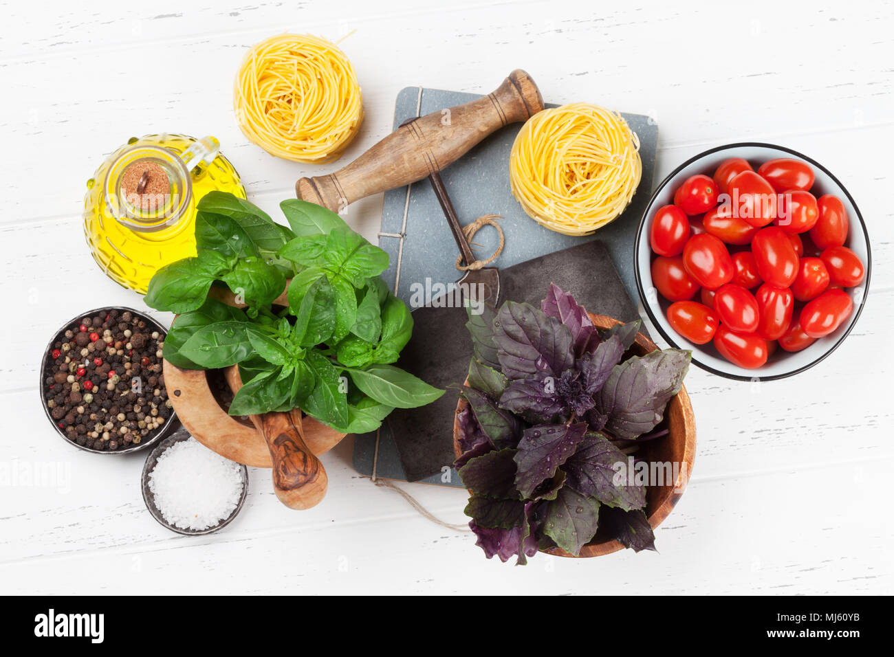 Italian cuisine. Basil, tomato, pasta and spices cooking. Top view ...