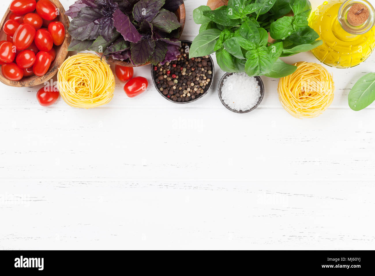 Italian cuisine. Basil, tomato, pasta and spices cooking. Top view with ...