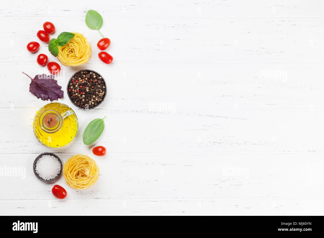 Italian cuisine. Basil, tomato, pasta and spices cooking. Top view with ...