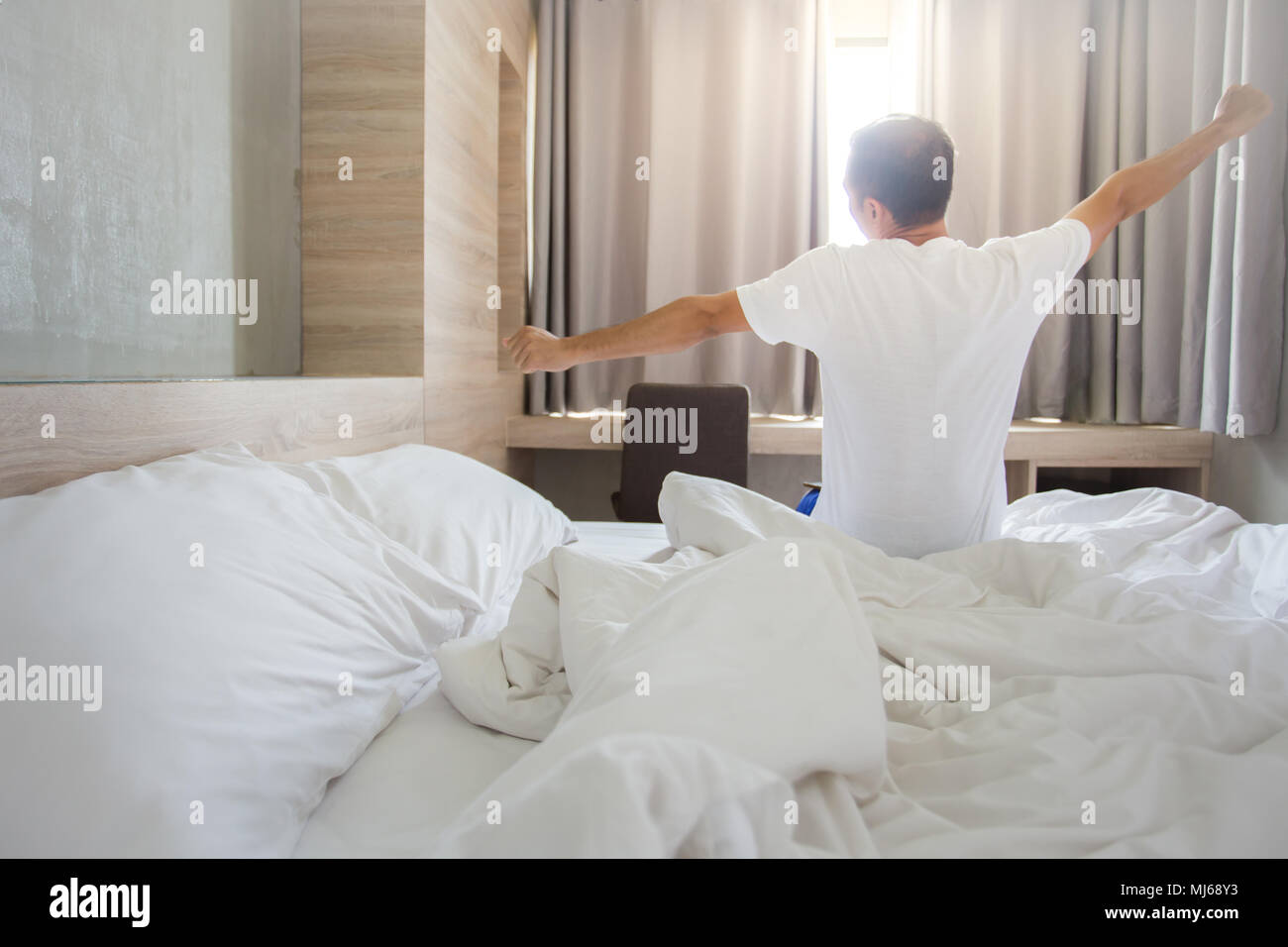 Morning of a new day, alarm clock waking up man stretch the muscles at ...