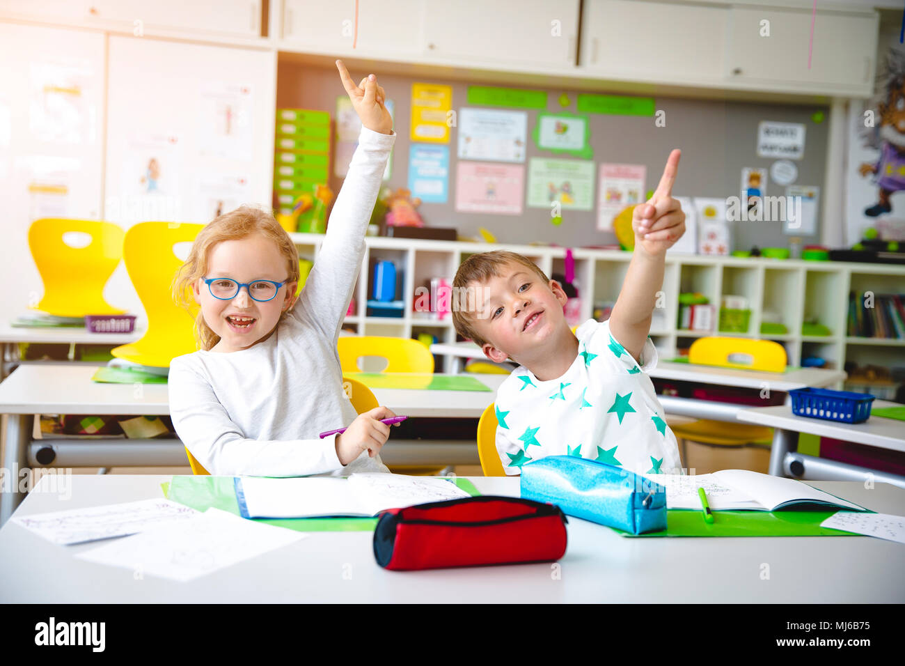 Beautiful young kids have fun in school while learning in classroom ...