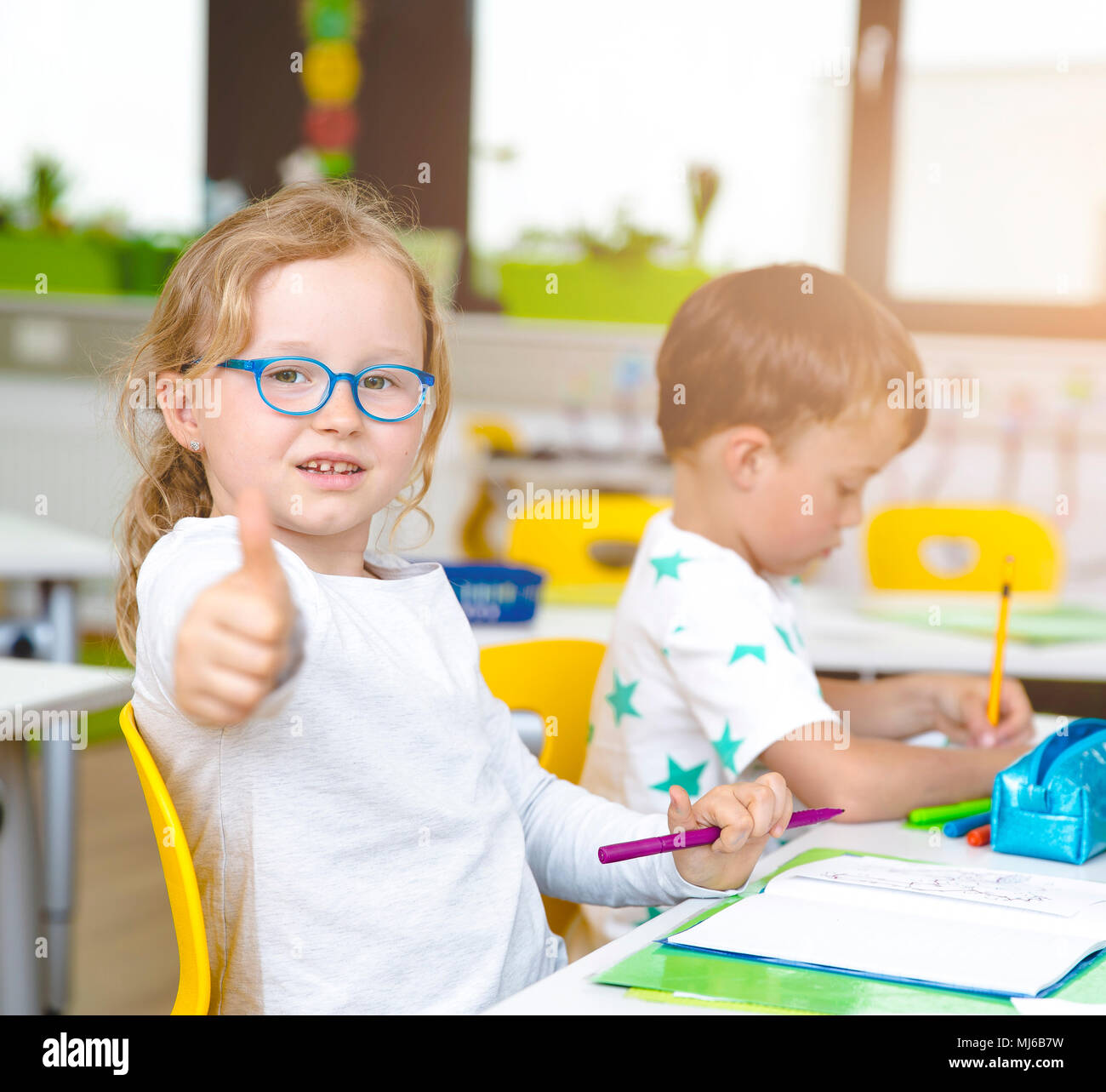 Beautiful young kids have fun in school while learning in classroom ...
