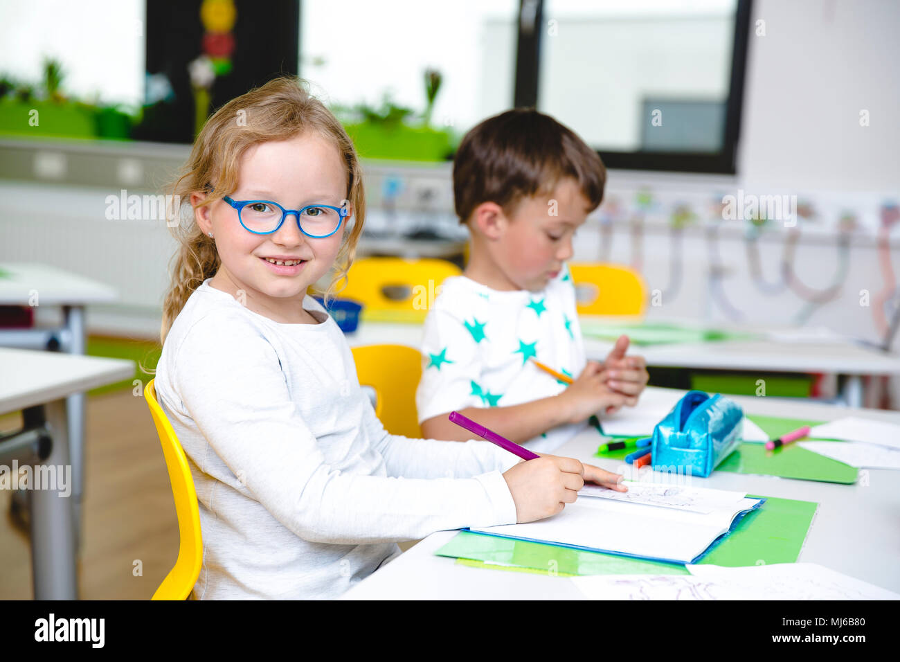 Beautiful young kids have fun in school while learning in classroom ...