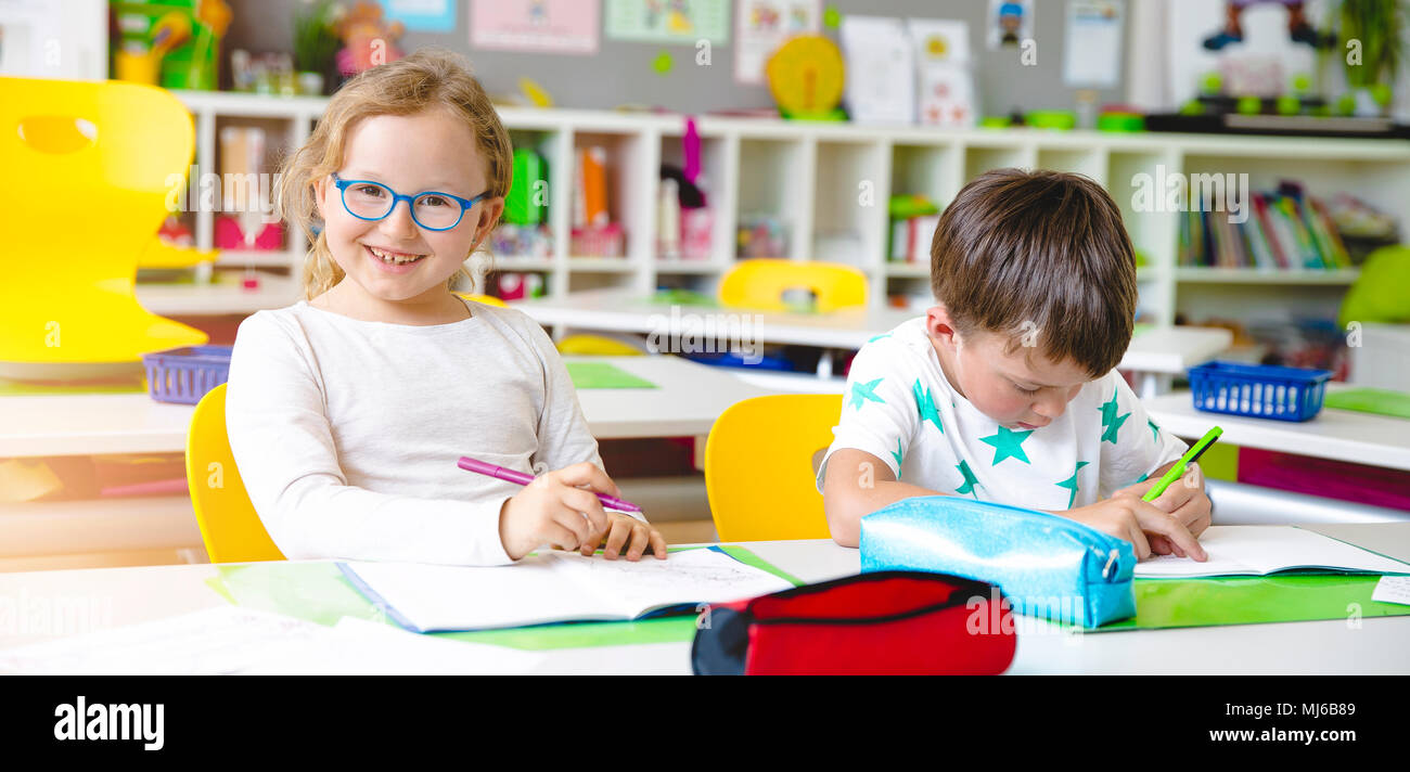 Beautiful young kids have fun in school while learning in classroom ...