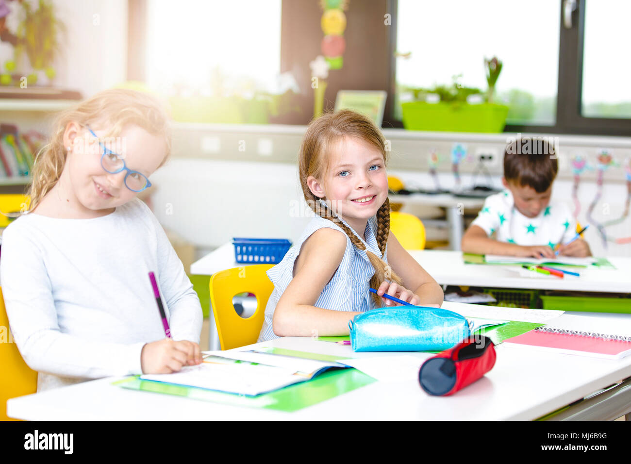 Beautiful young kids have fun in school while learning in classroom ...