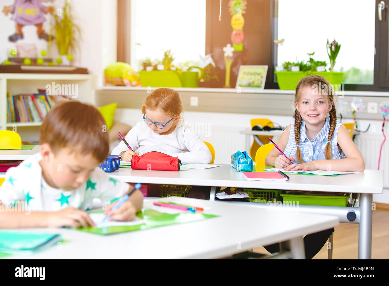 Beautiful young kids have fun in school while learning in classroom ...