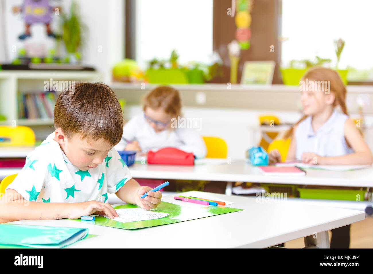 Beautiful young kids have fun in school while learning in classroom ...