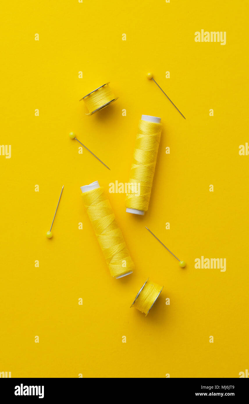 Colorful yellow thread spools over bright yellow background, above view ...