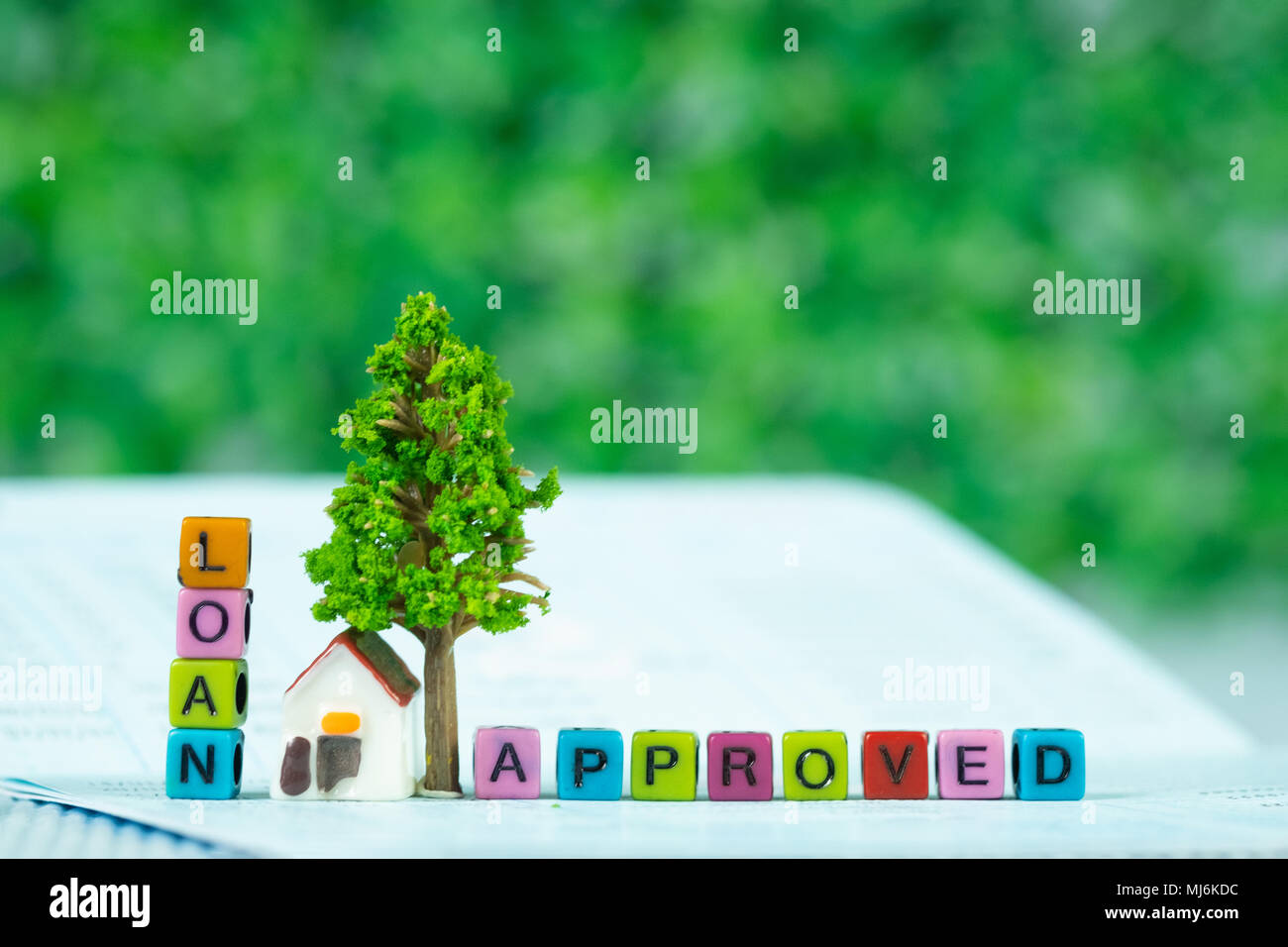 LOAN text and small model house and little tree with notebook, savings ...