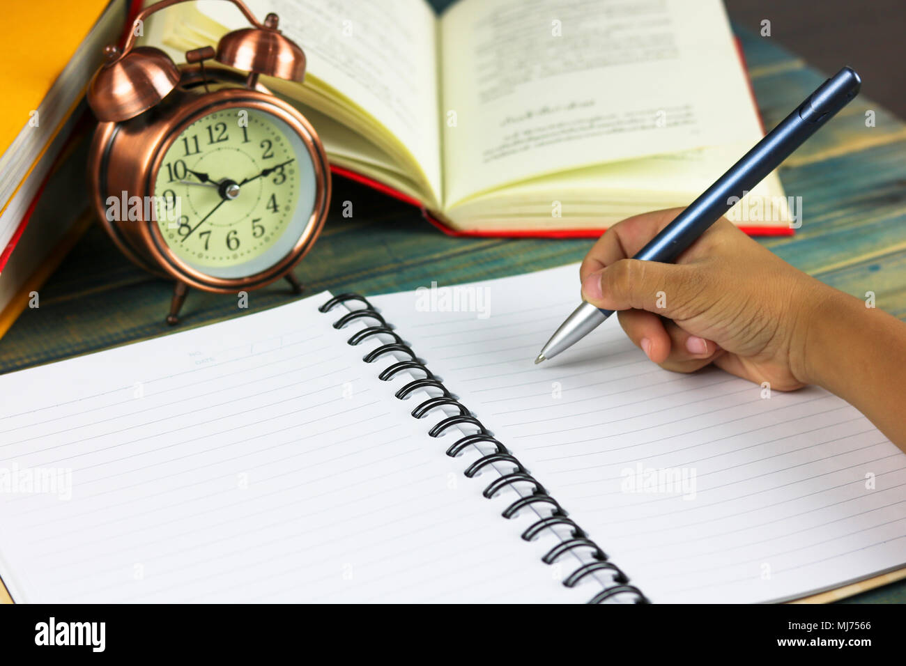 hand writing with books and clock on desk Stock Photo - Alamy