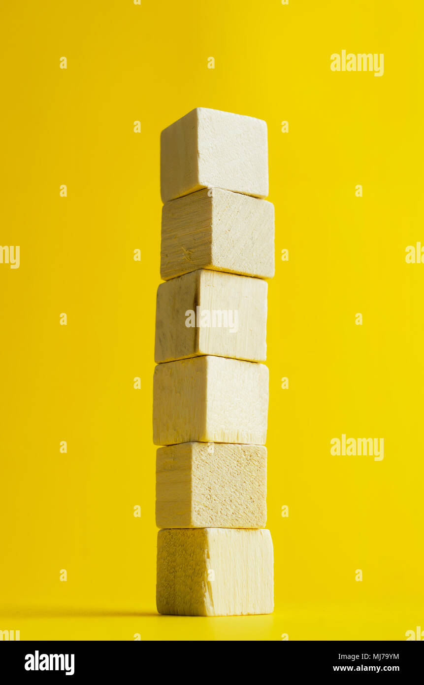 Stack of wooden cubes over bright yellow background Stock Photo - Alamy