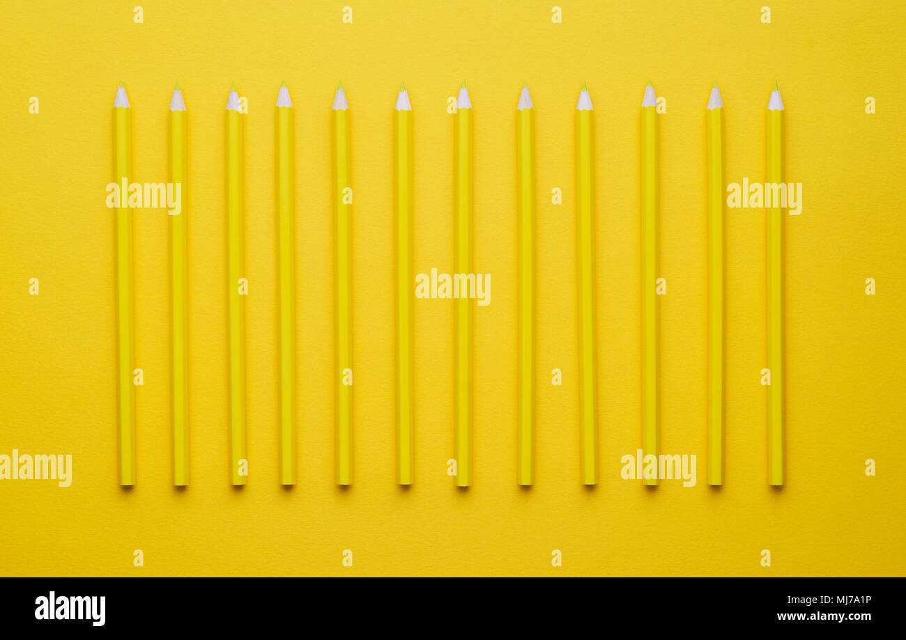 Yellow crayons organized in a row over yellow background, above view ...