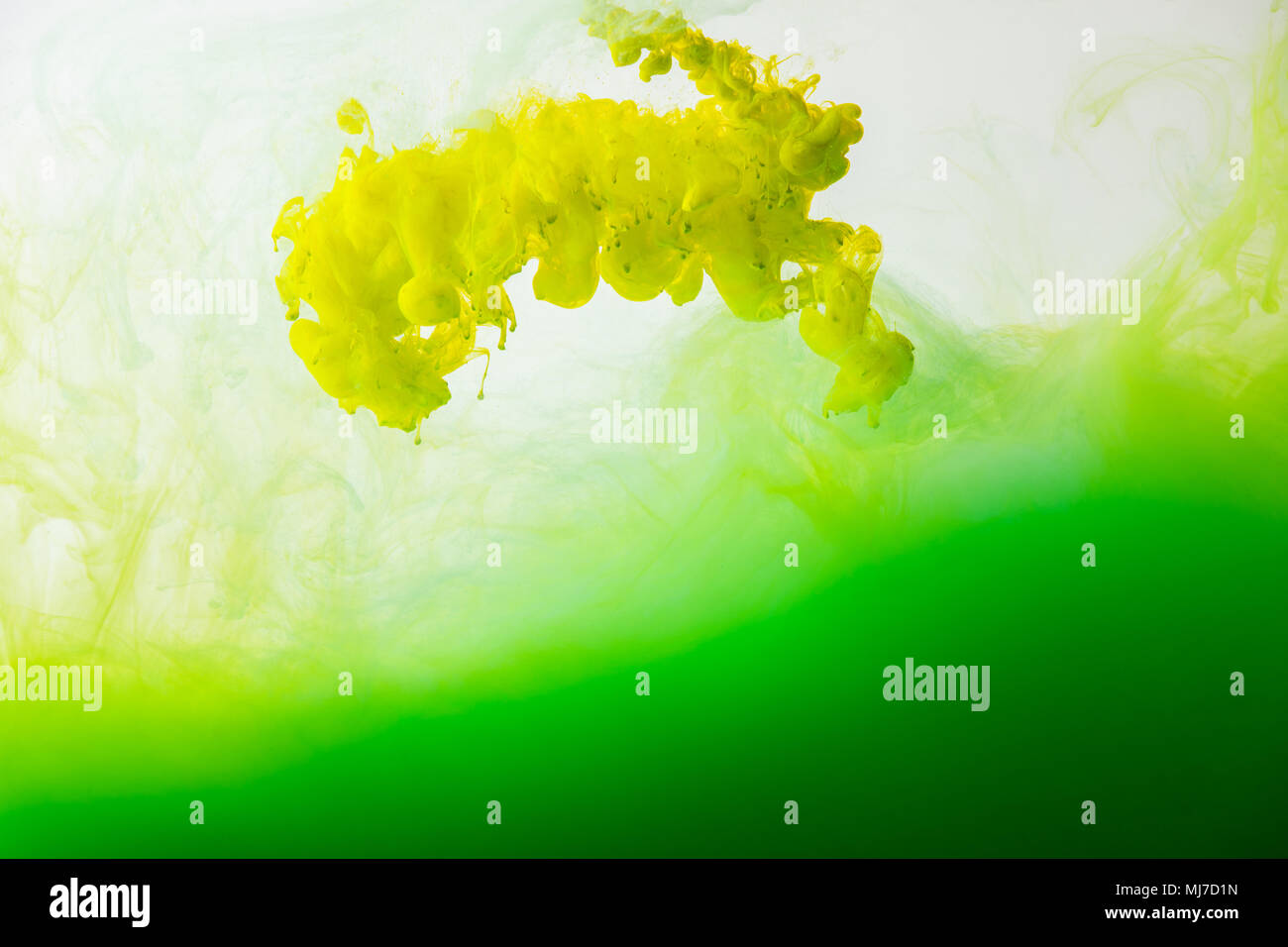 close up view of mixing of green and yellow paints splashes in water ...