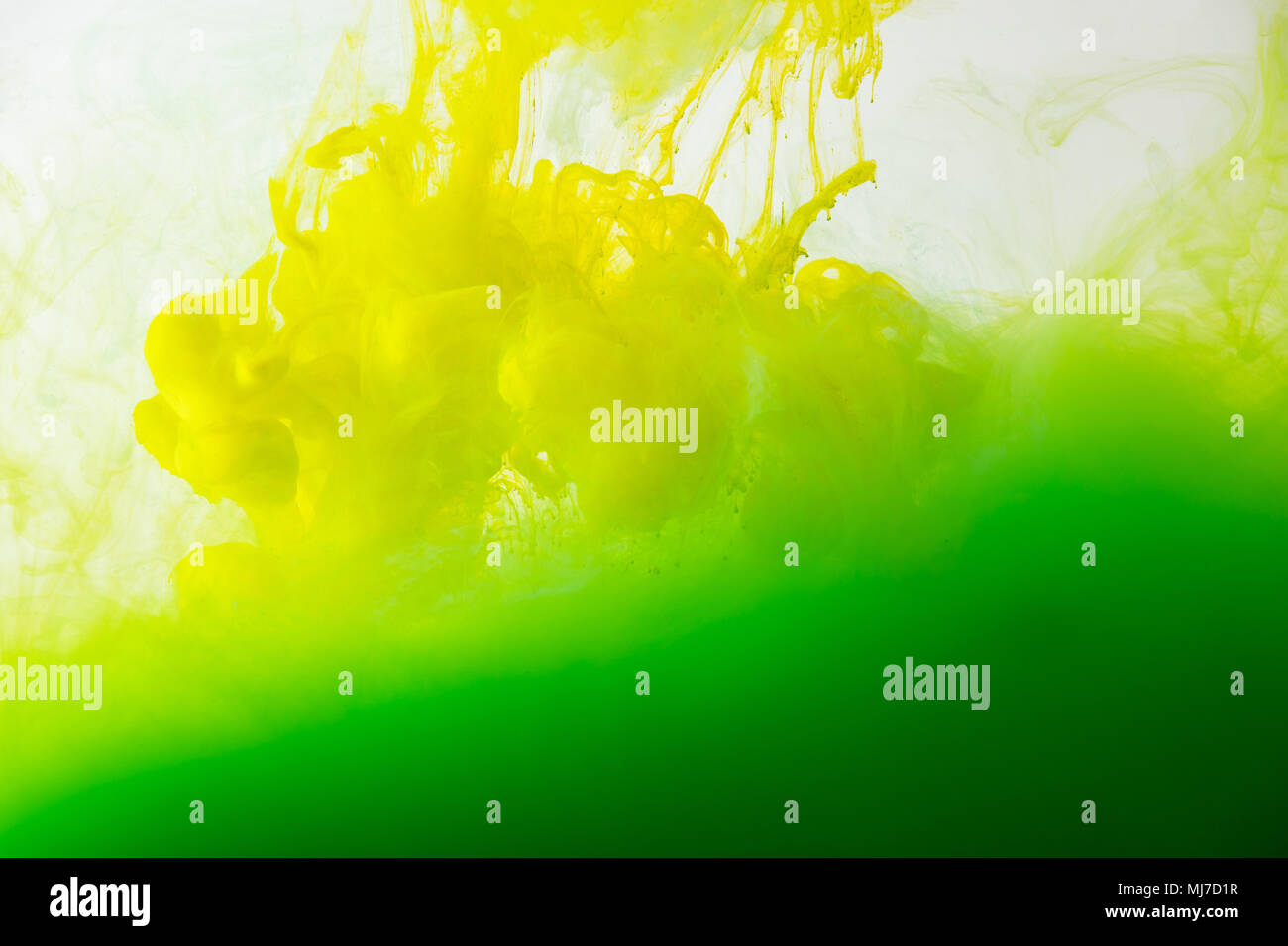 close up view of mixing of green and yellow paints splashes in water ...