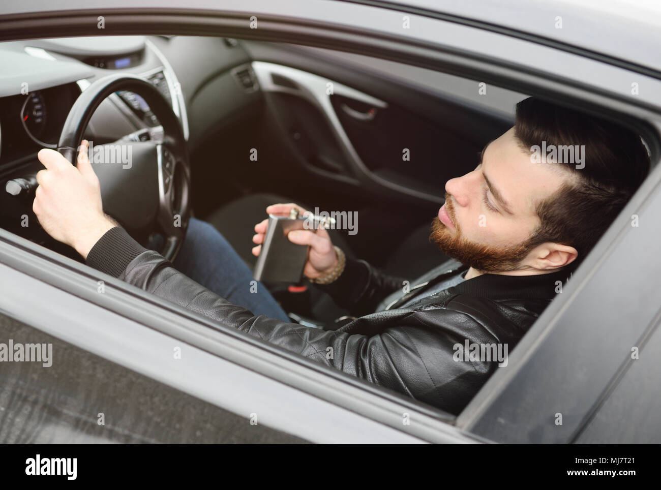 Young man driving a car with an iron flask Stock Photo - Alamy