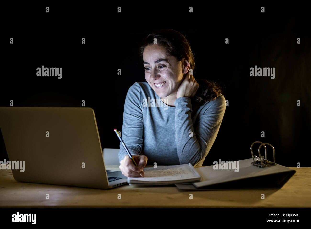 Overworked and tired female student working last at night on her laptop ...