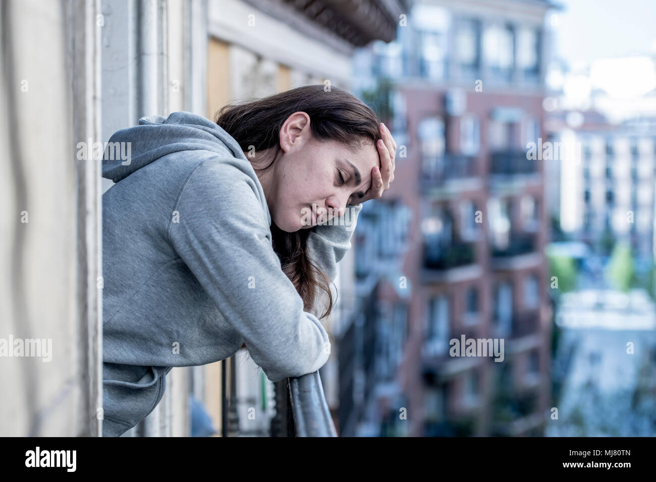young Latin. sad and depressed woman standing on a balcony feeling over ...