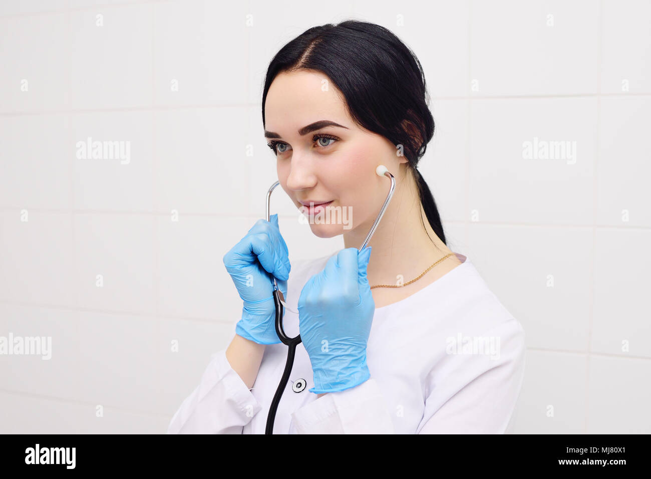 young pretty doctor girl in white medical dressing gown with ...