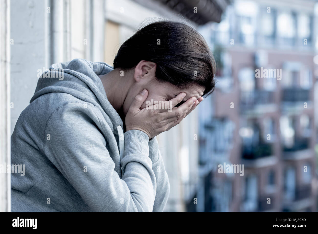 young Latin. sad and depressed woman standing on a balcony feeling over ...