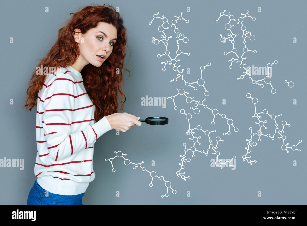 Skilled scientist holding a magnifying glass while making an experiment ...