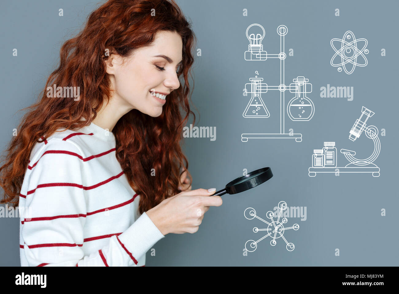 Positive laboratory worker smiling while using a magnifying glass Stock ...