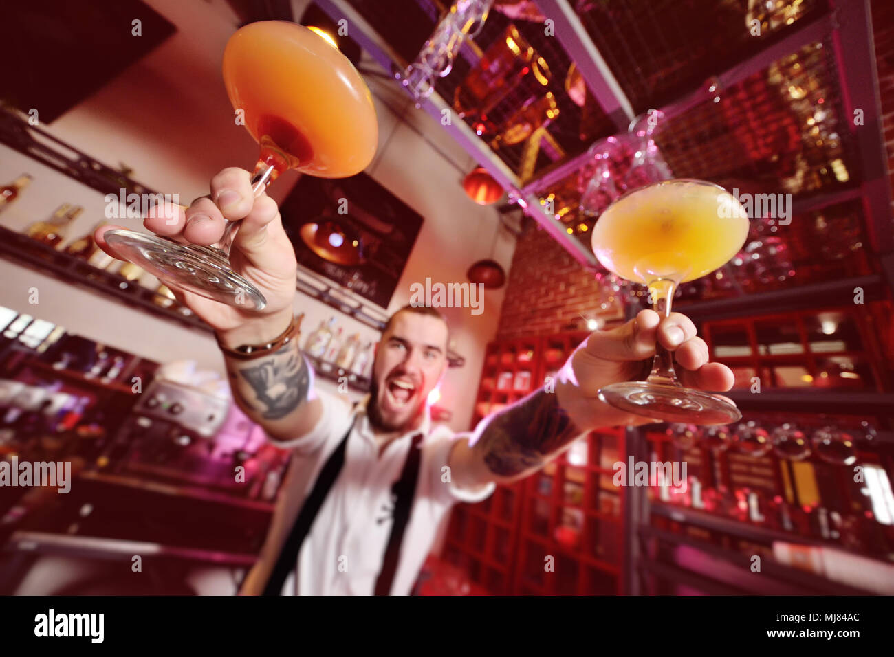 young bartender smiling and giving the client a cocktail of orange ...