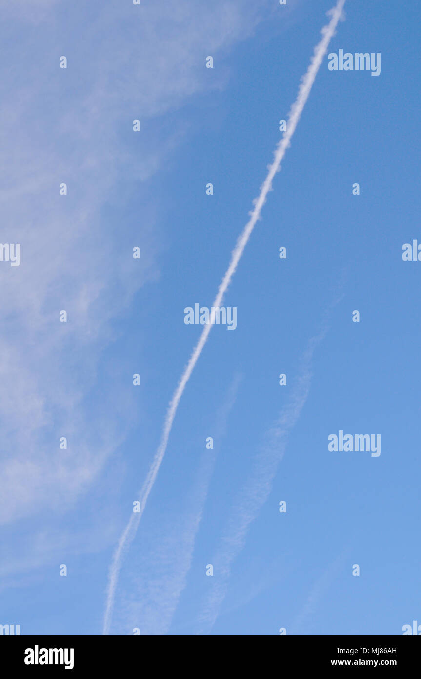 Airplane trails in theblue sky vertical photo Stock Photo - Alamy