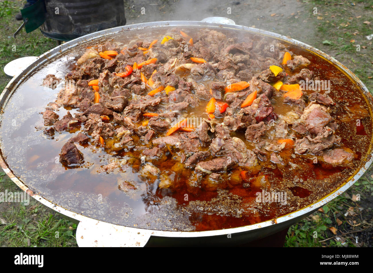 Cauldron full of stewed meat set on moveable wood stoves. Celebration ...