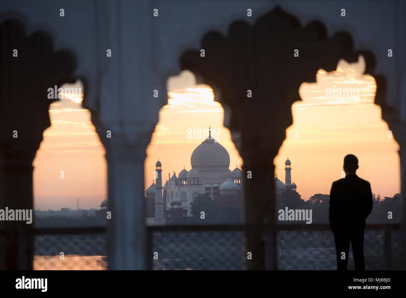 Rear view of man standing underneath scalloped arch on balcony at ...