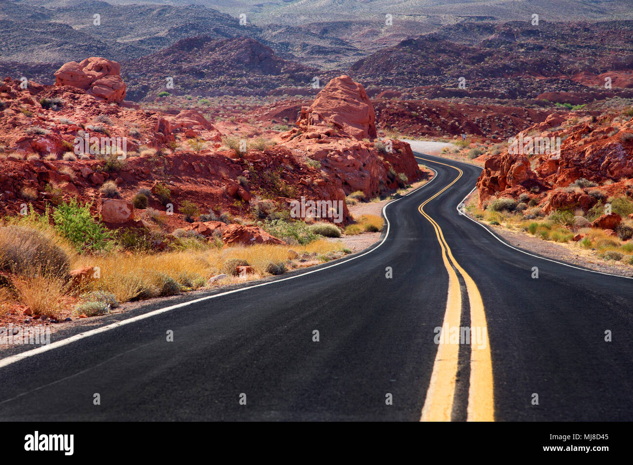 Rural road winding through remote mountain landscape with red rocks ...